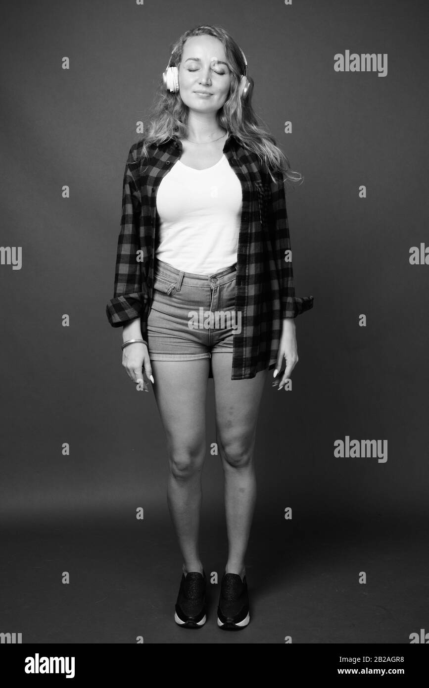 Young beautiful woman with long wavy blond hair against gray background ...