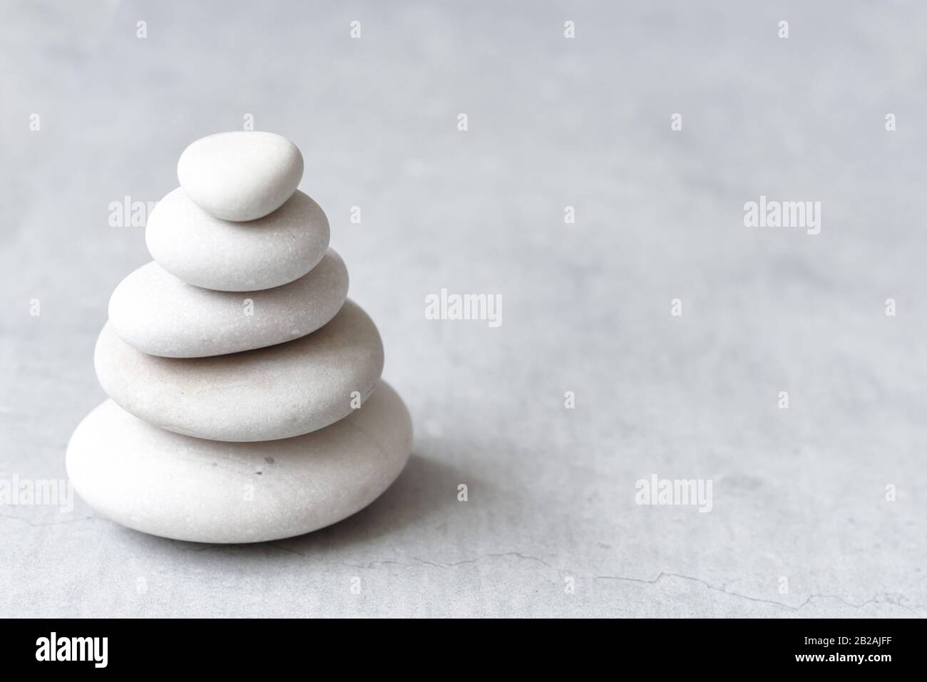 Stack of white pebbles on a neutral light grey background as balance ...