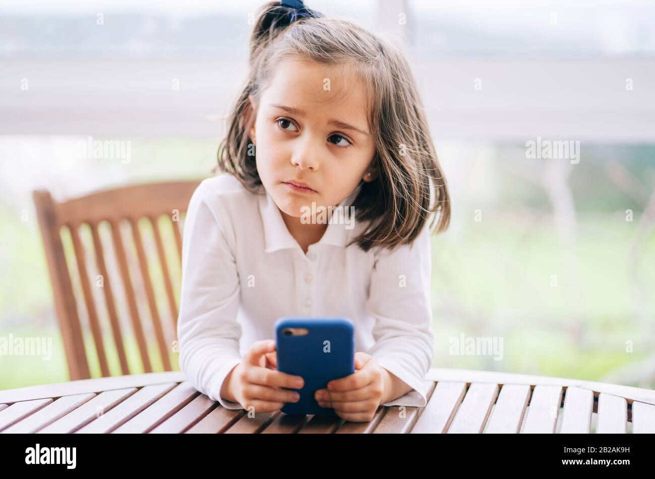 A little girl uses mobile phone smartphone at home Stock Photo - Alamy