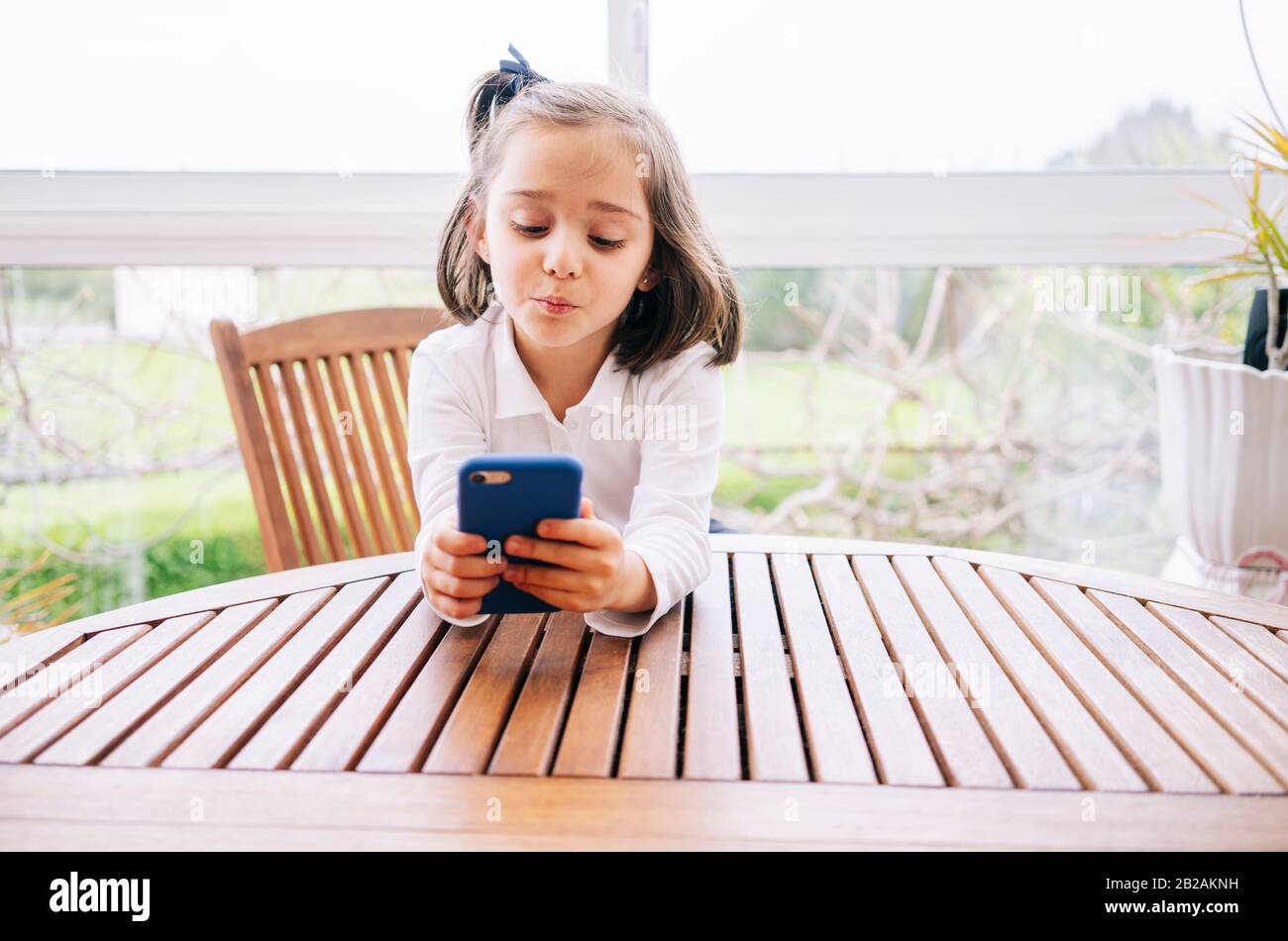 A little girl uses mobile phone smartphone at home Stock Photo - Alamy