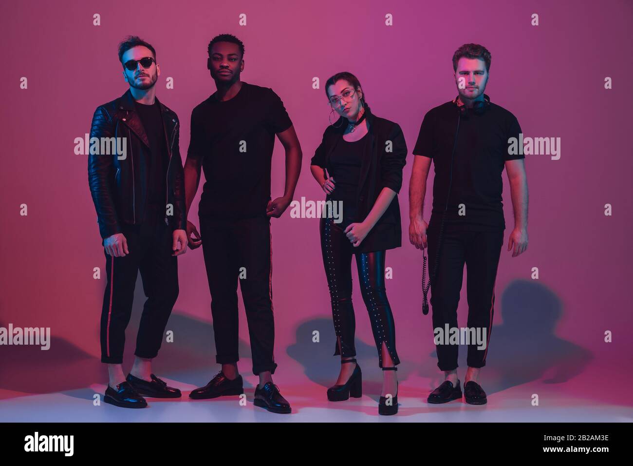 Group of young multiethnic musicians created band, dancing in neon ...