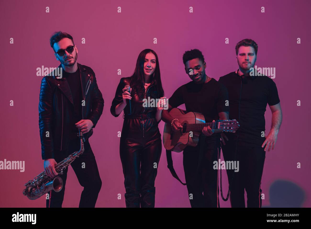 Group of young multiethnic musicians created band, dancing in neon ...