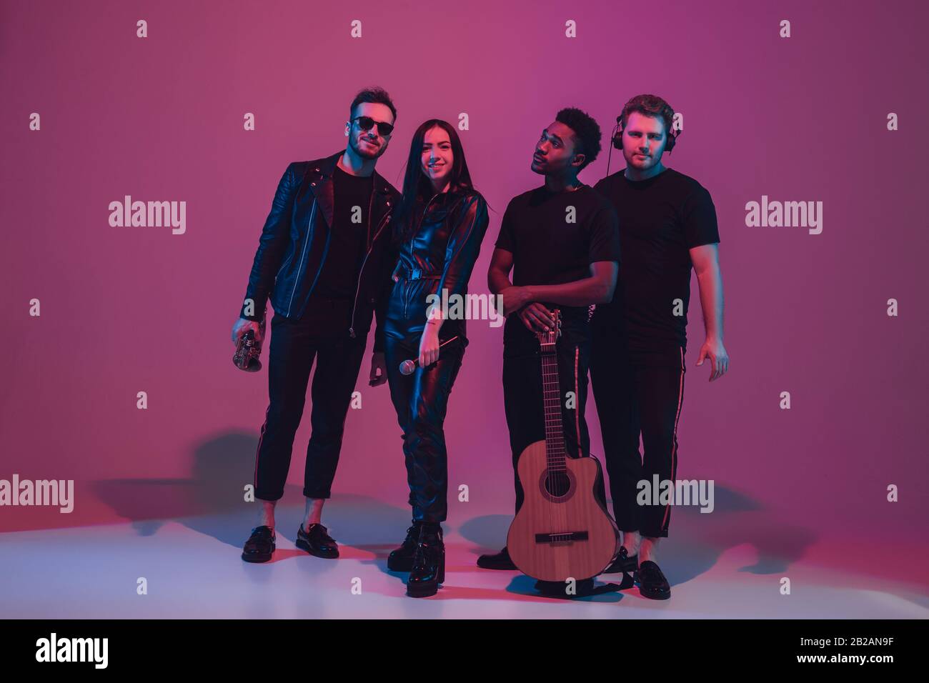 Group of young multiethnic musicians created band, dancing in neon ...