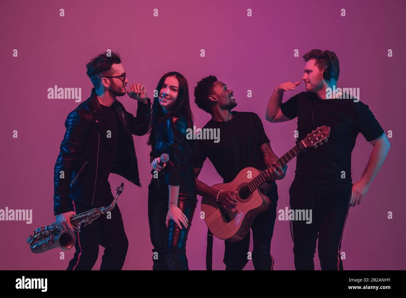 Group of young multiethnic musicians created band, dancing in neon ...