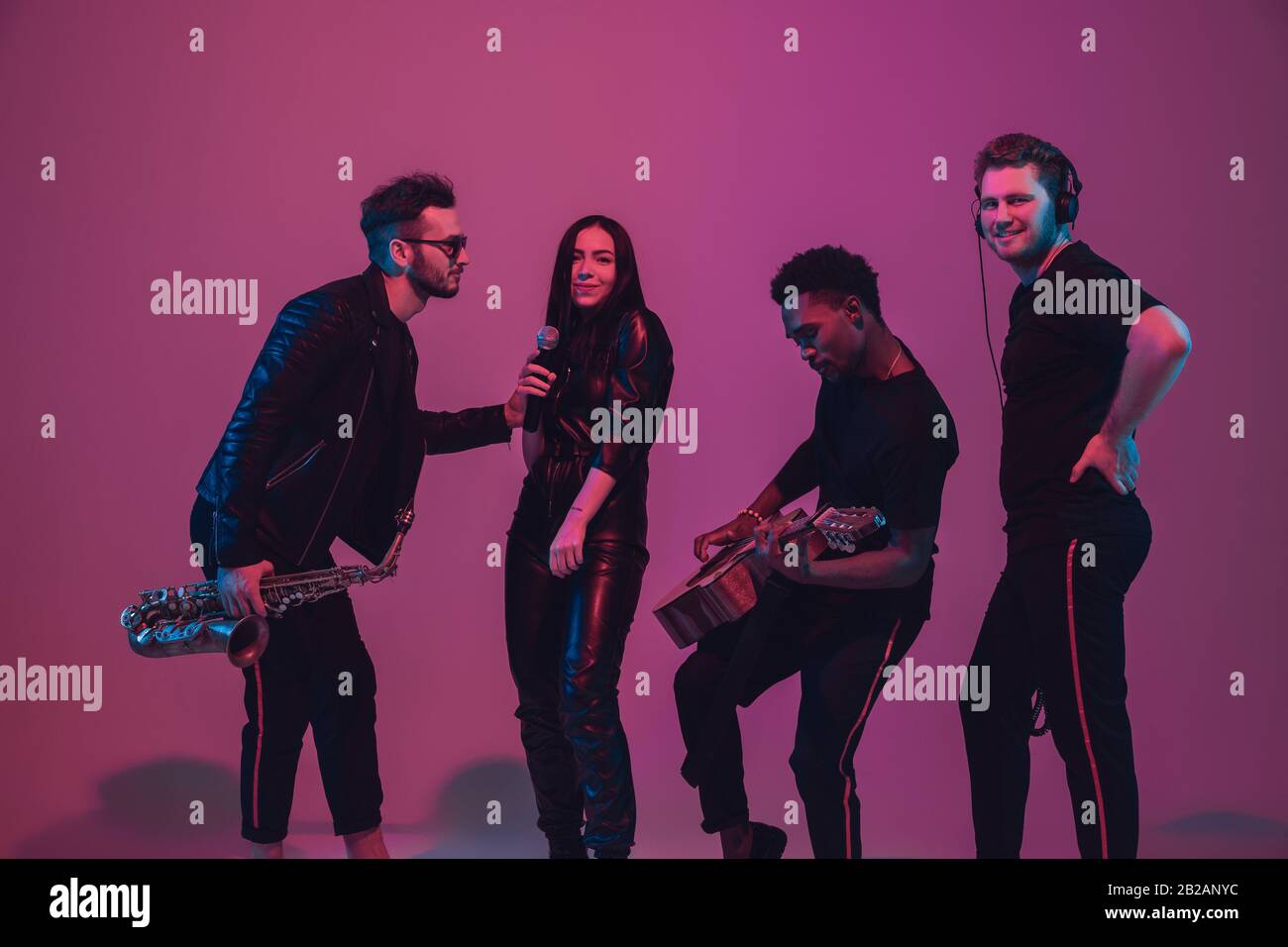 Group of young multiethnic musicians created band, dancing in neon ...