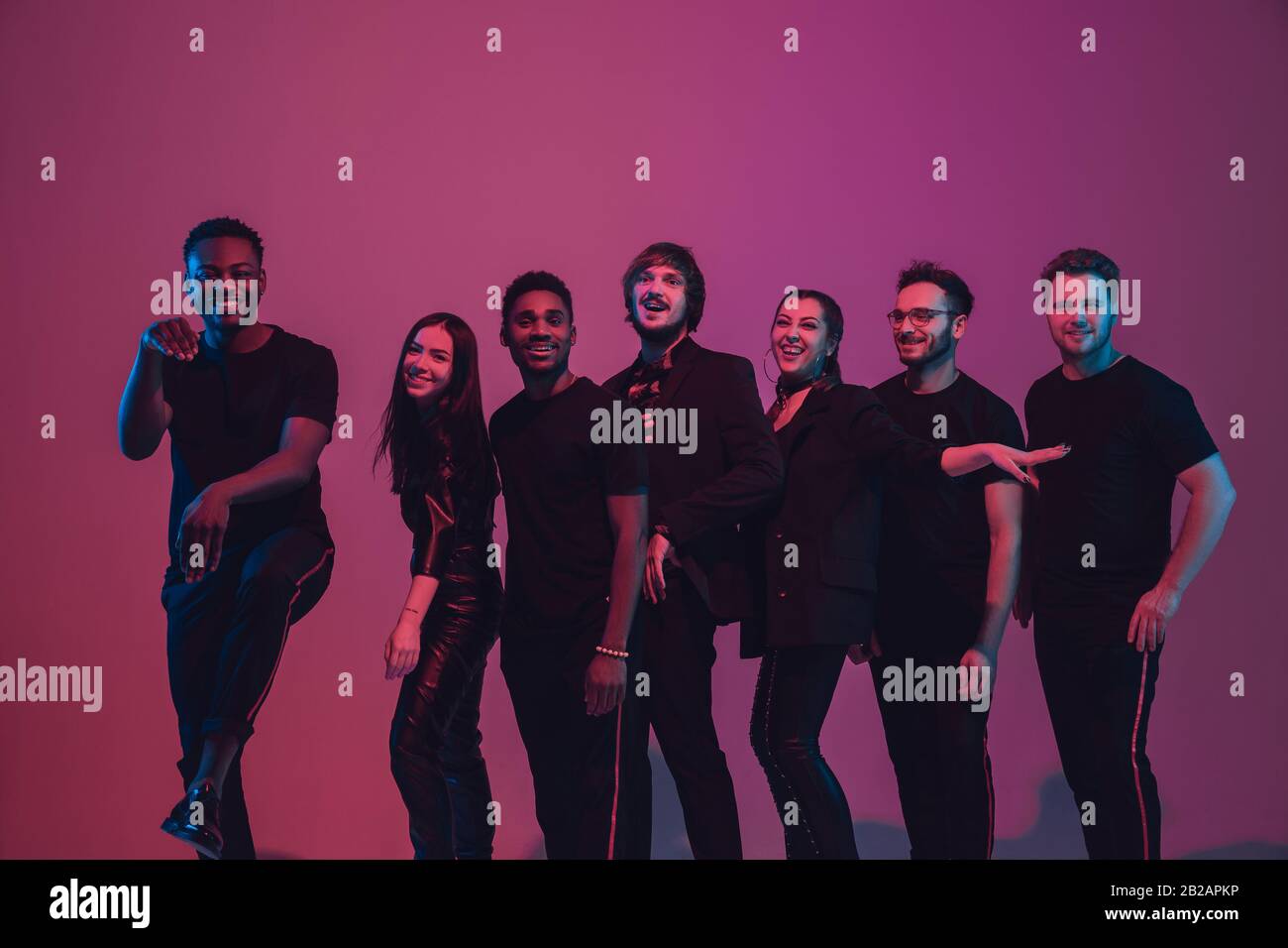 Group of young multiethnic musicians created band, dancing in neon ...