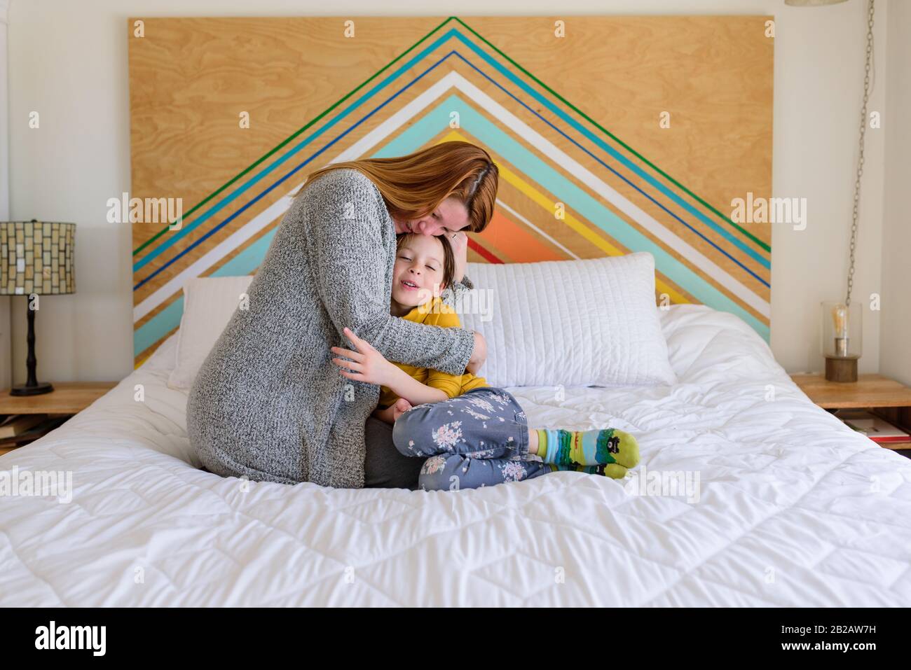 Mother and daughter sitting on a bed cuddling Stock Photo - Alamy