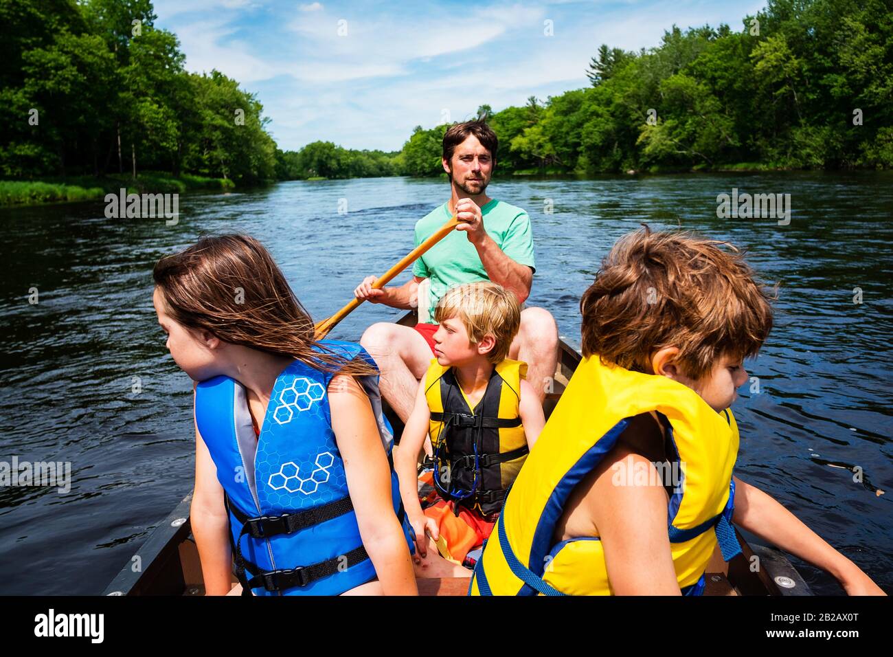 Father canoeing along a river with his three children, USA Stock Photo ...