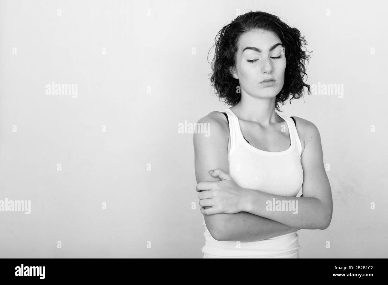 Studio shot of angry teenage girl thinking while looking down with arms ...