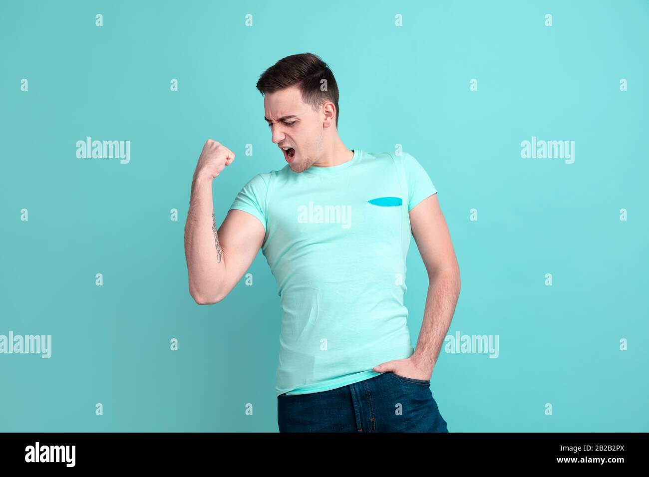Power, strenght. Caucasian young man's portrait isolated on blue studio ...