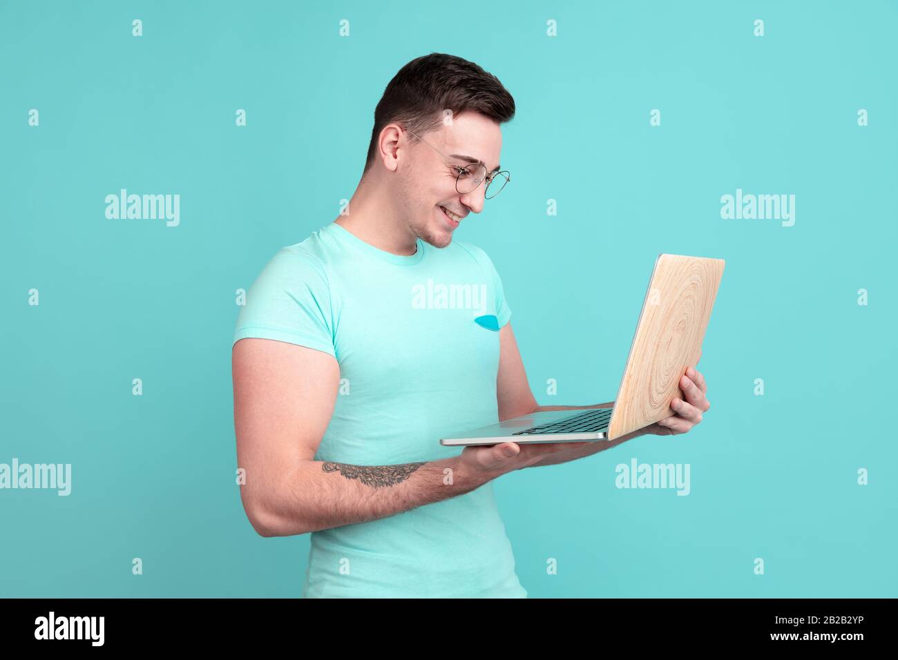 Using laptop. Caucasian young man's portrait isolated on blue studio ...