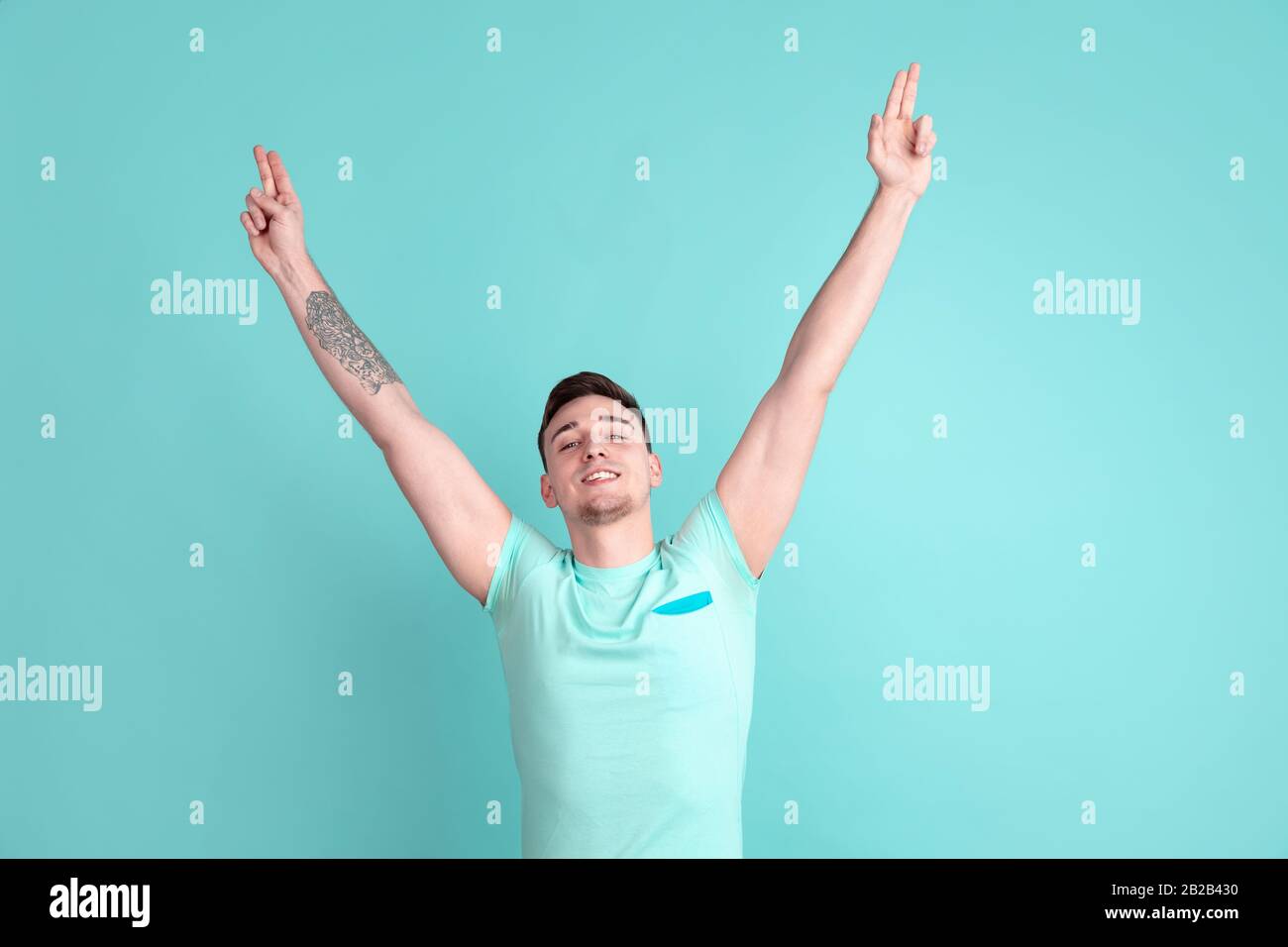 Pointing, winning. Caucasian young man's portrait isolated on blue ...