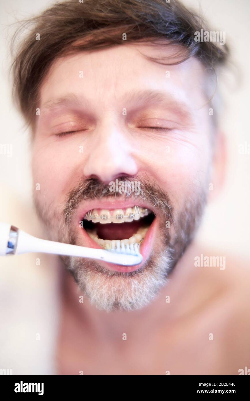 Man brushing his teeth with an electric toothbrush Stock Photo - Alamy