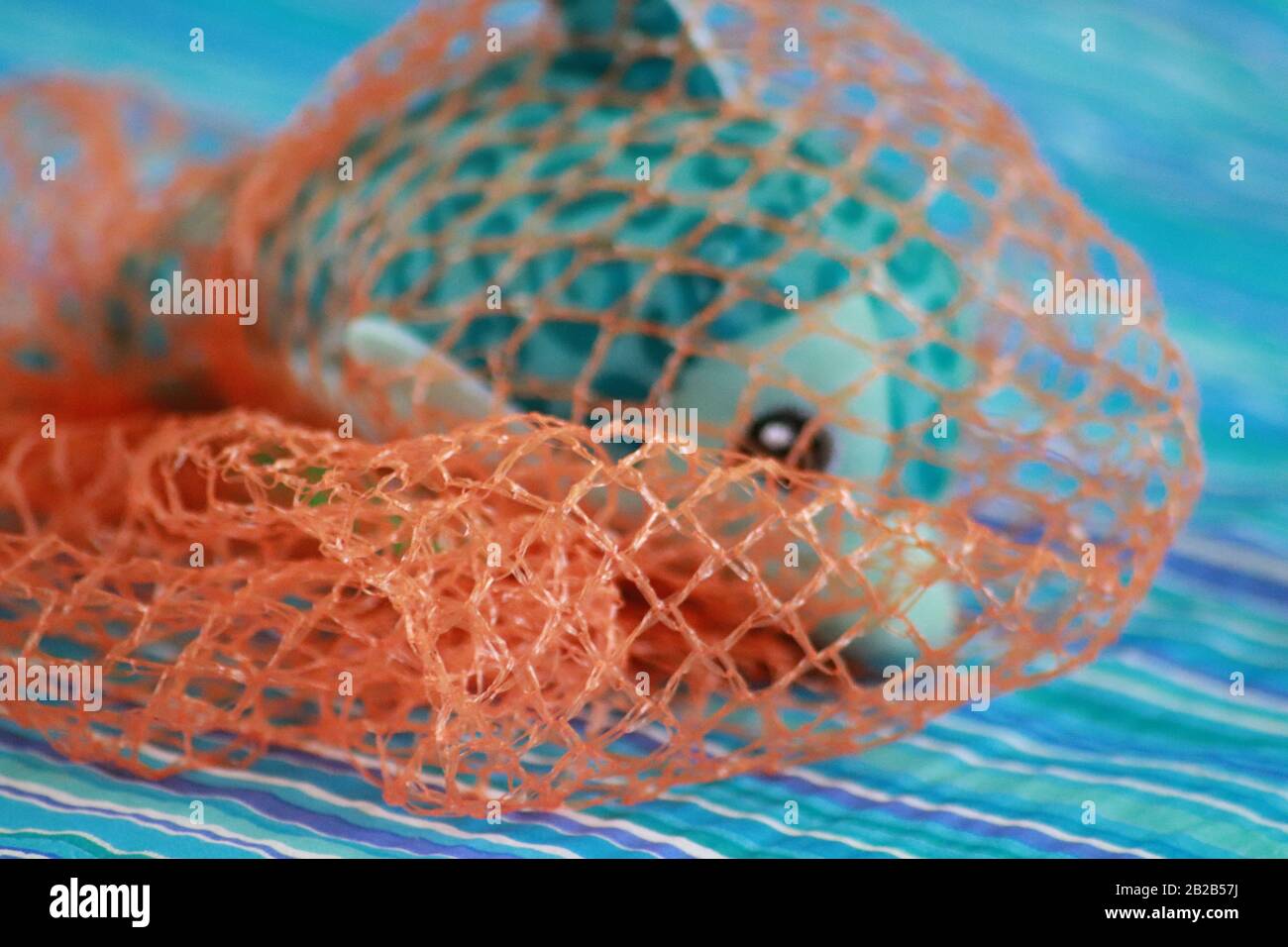Plush fish trapped in orange net Stock Photo - Alamy