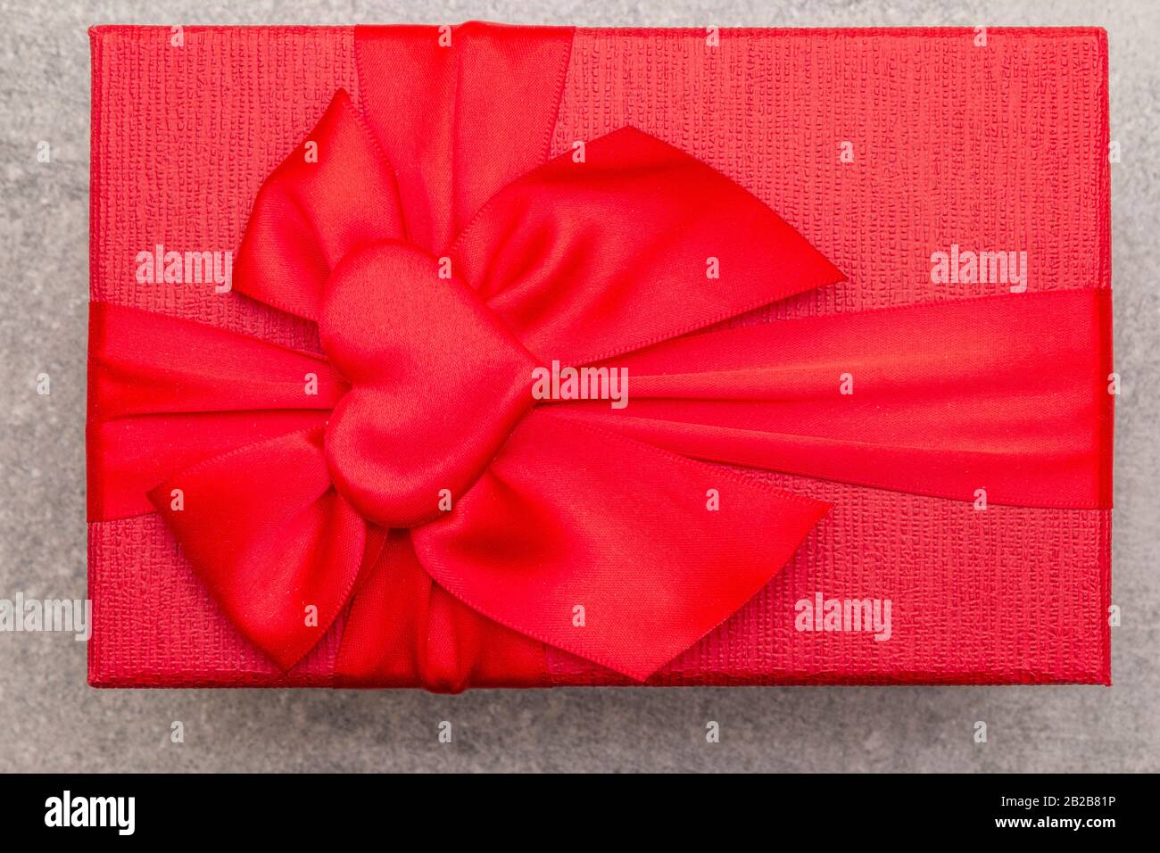 Romantic gift concept. Red box with bow on a stone background, top view ...