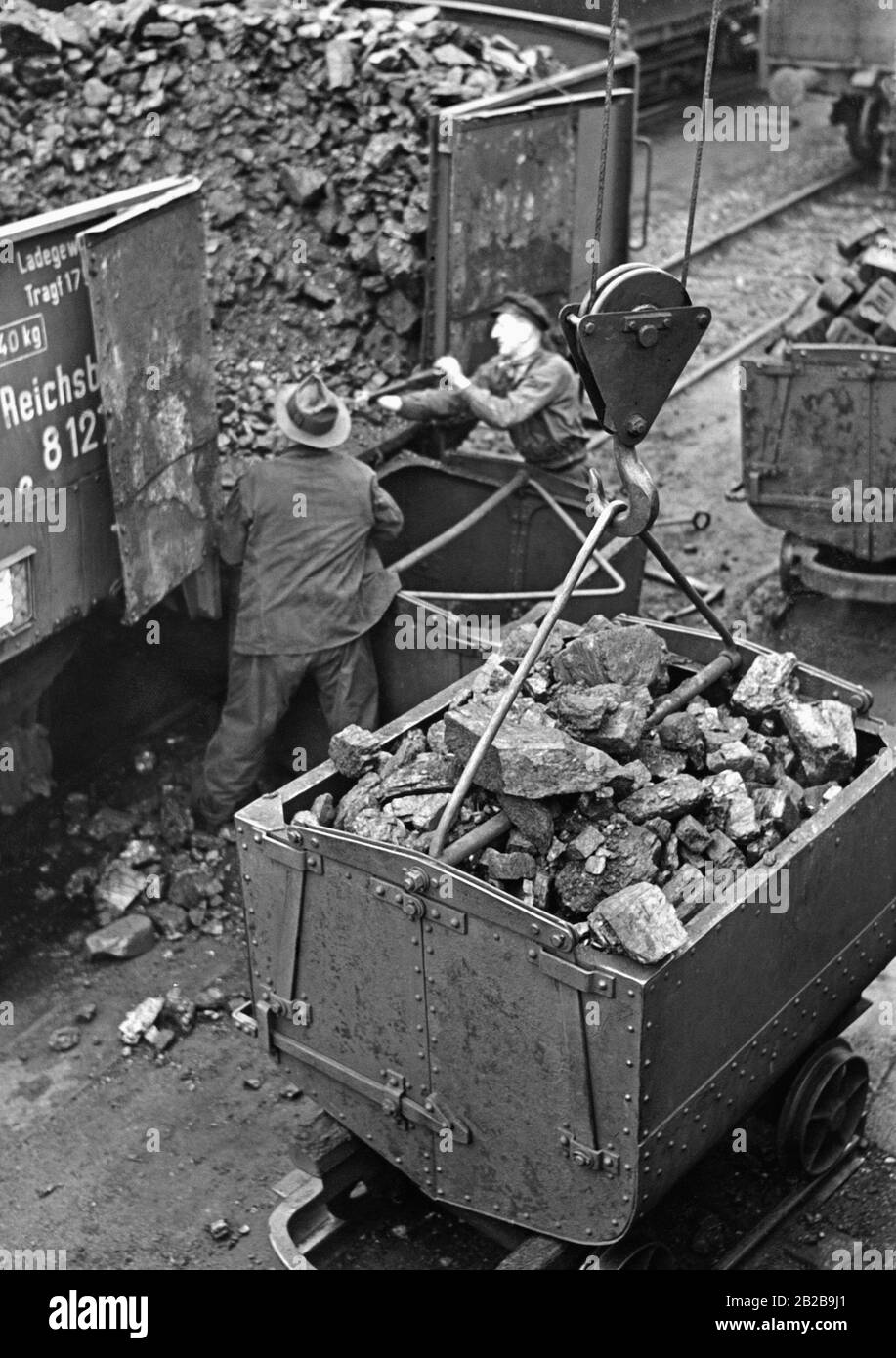 Workers loading coal, that is required to run the steam locomotive ...