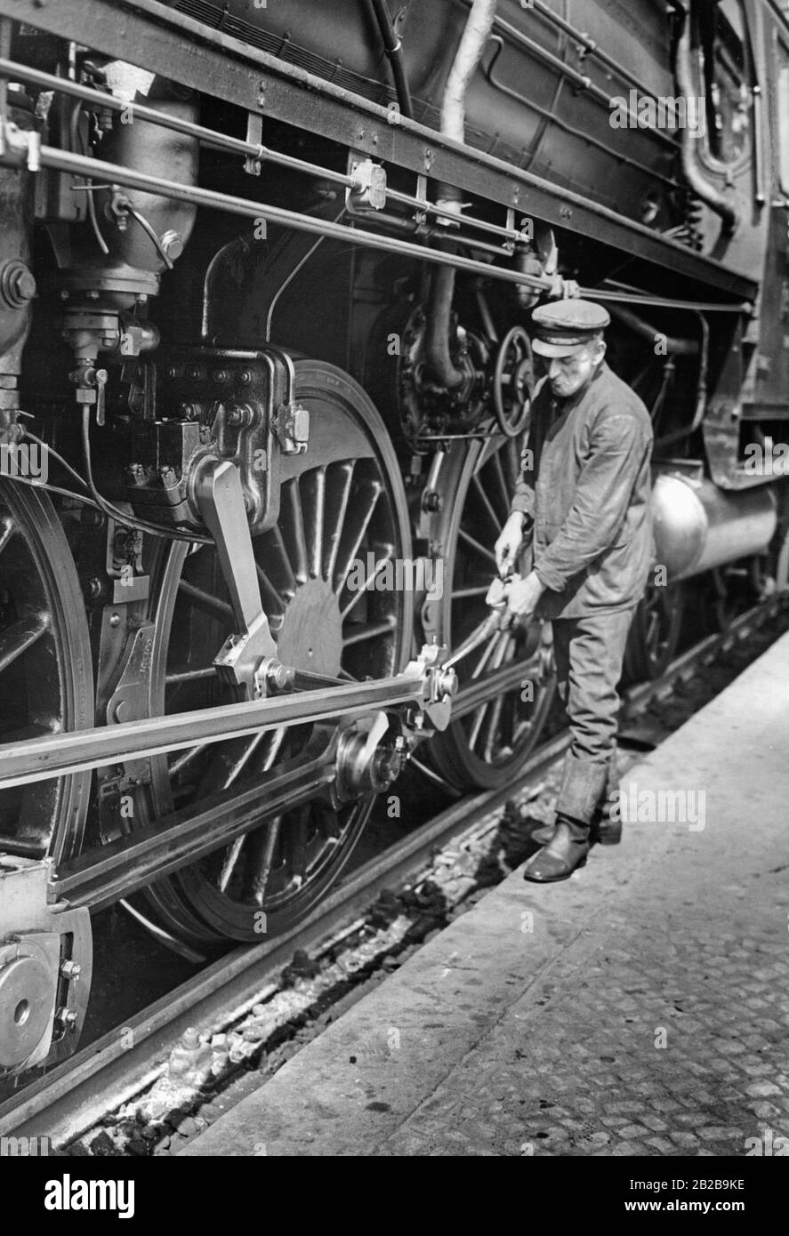 A railway employee when greasing the drive wheels of a locomotive Stock ...