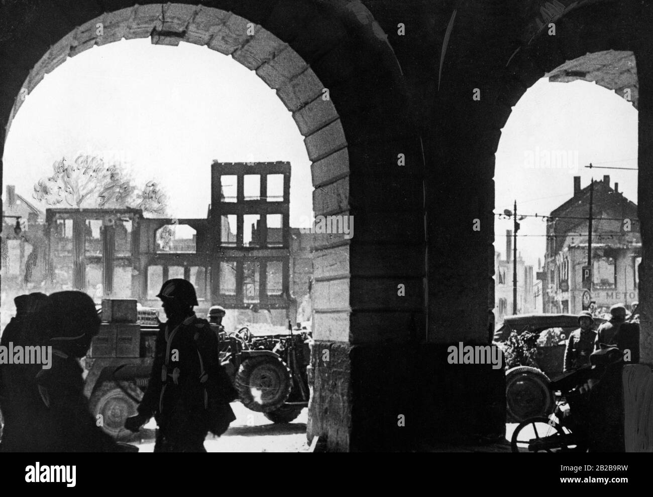 German military groups on the march. In the background are the ruins of ...