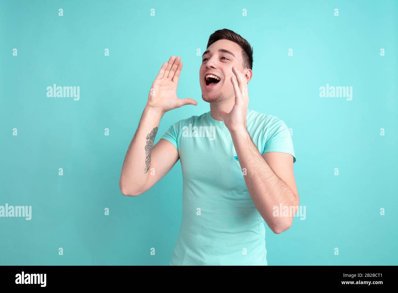 Calling, shouting. Caucasian young man's portrait isolated on blue ...