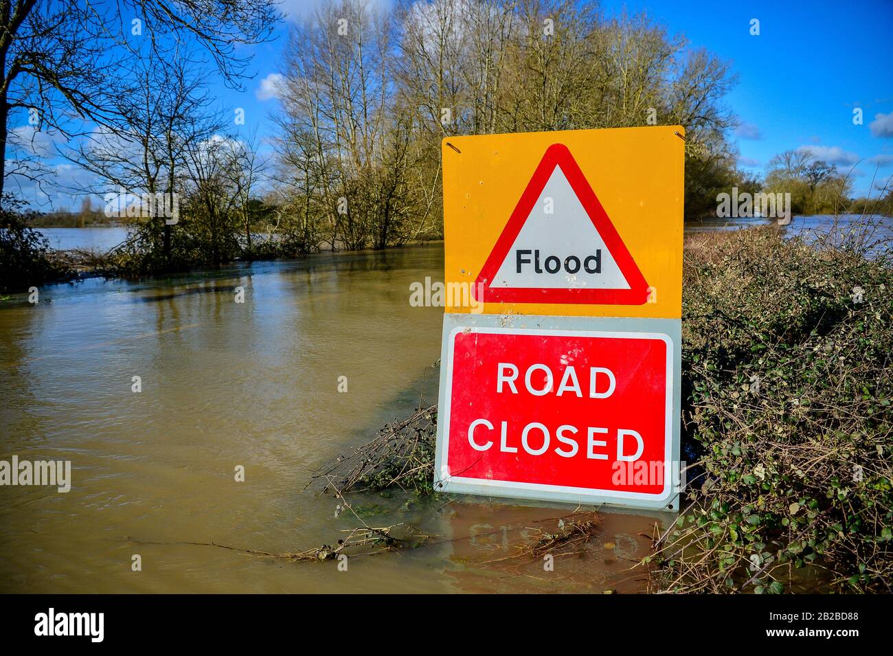 A road closed sign pokes out above floodwater and alerts motorists of ...