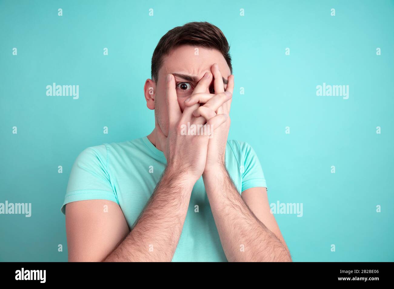Looks scared. Caucasian young man's portrait isolated on blue studio ...