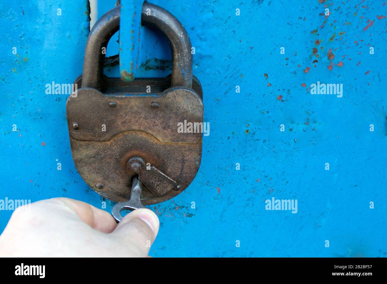 Old rusty lock with a key on a blue background Stock Photo - Alamy