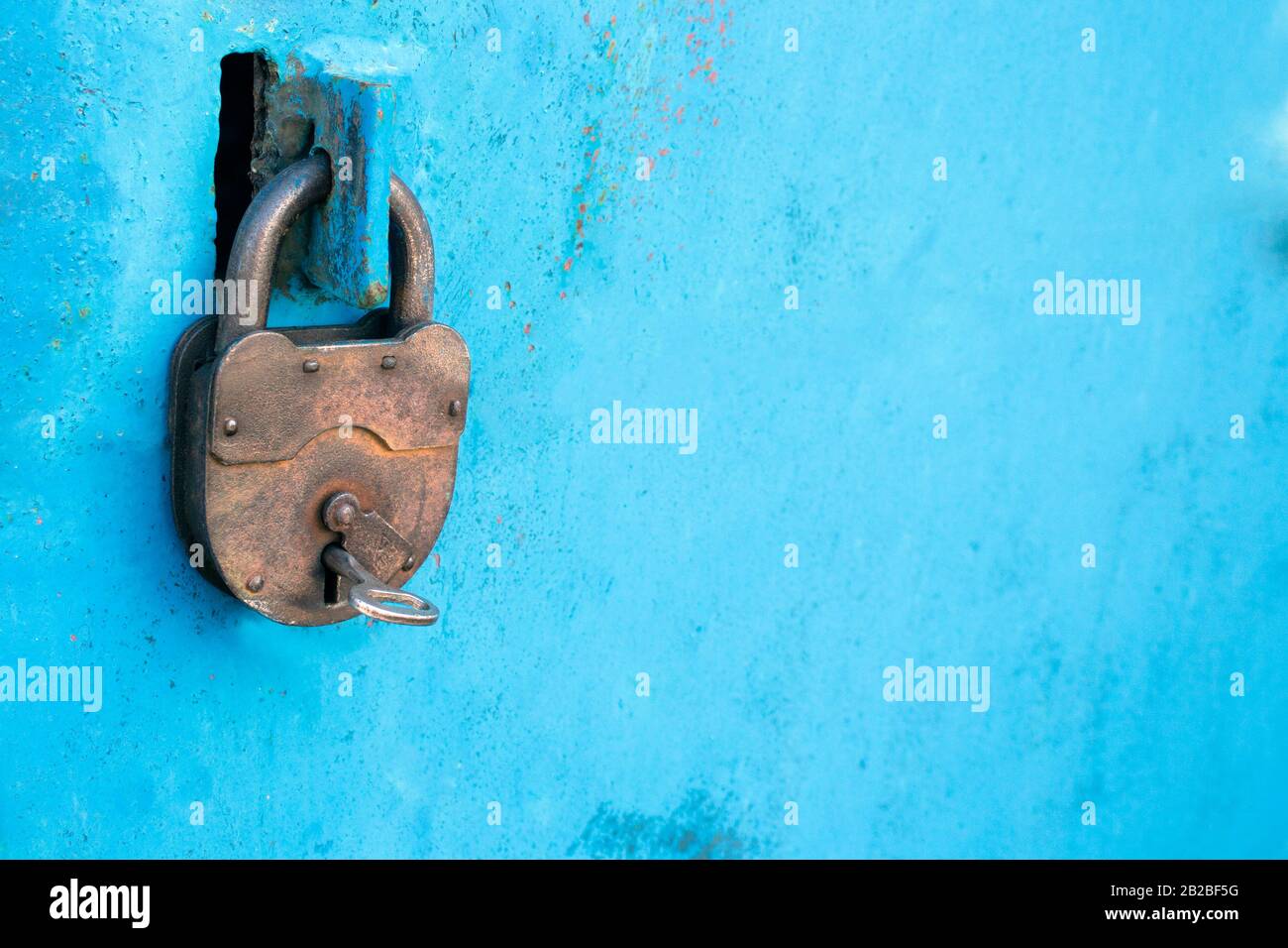 Old rusty lock with a key on a blue background Stock Photo - Alamy