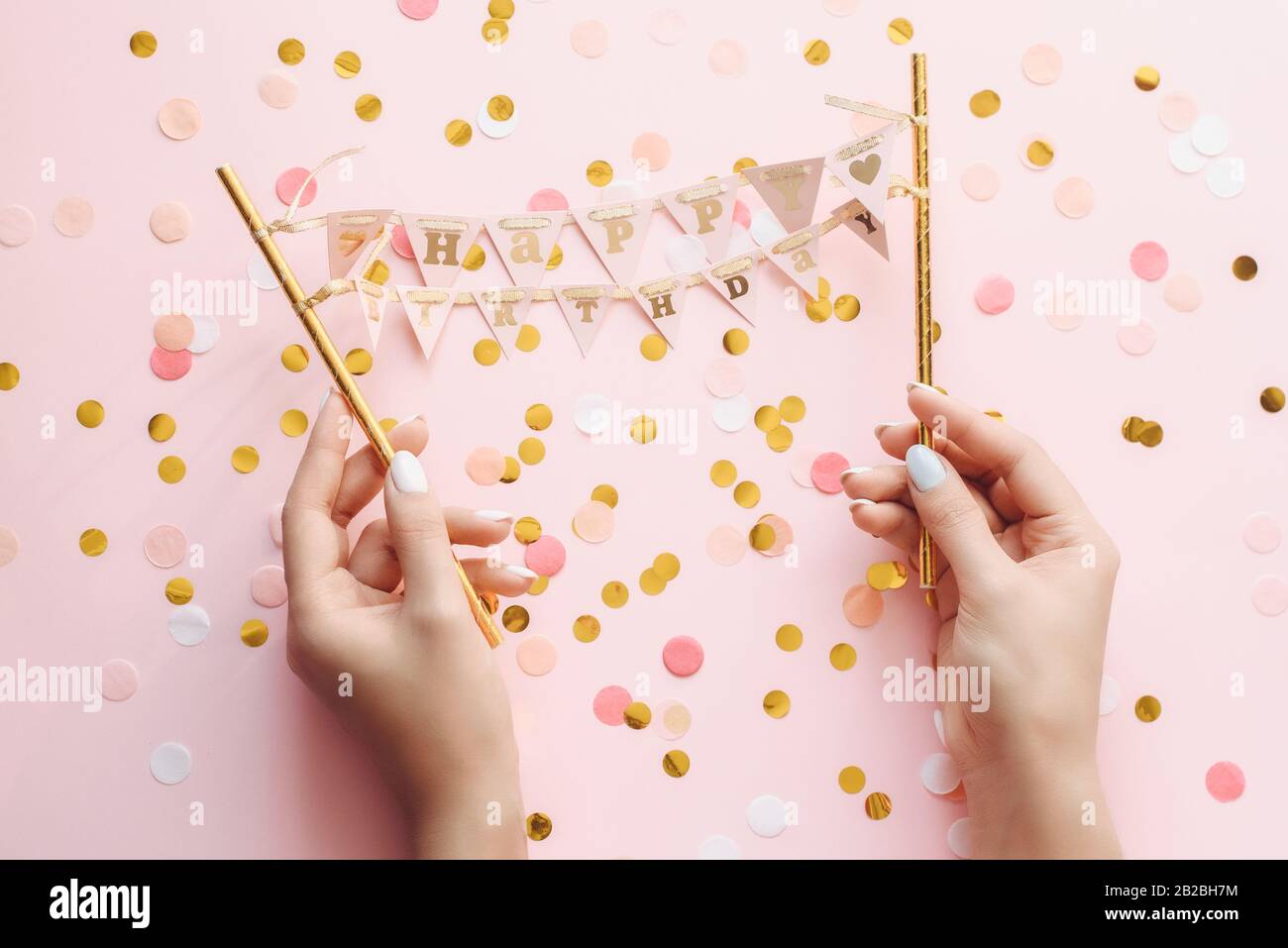 Woman's hand with pastel manicure holds a small banner happy birthday ...