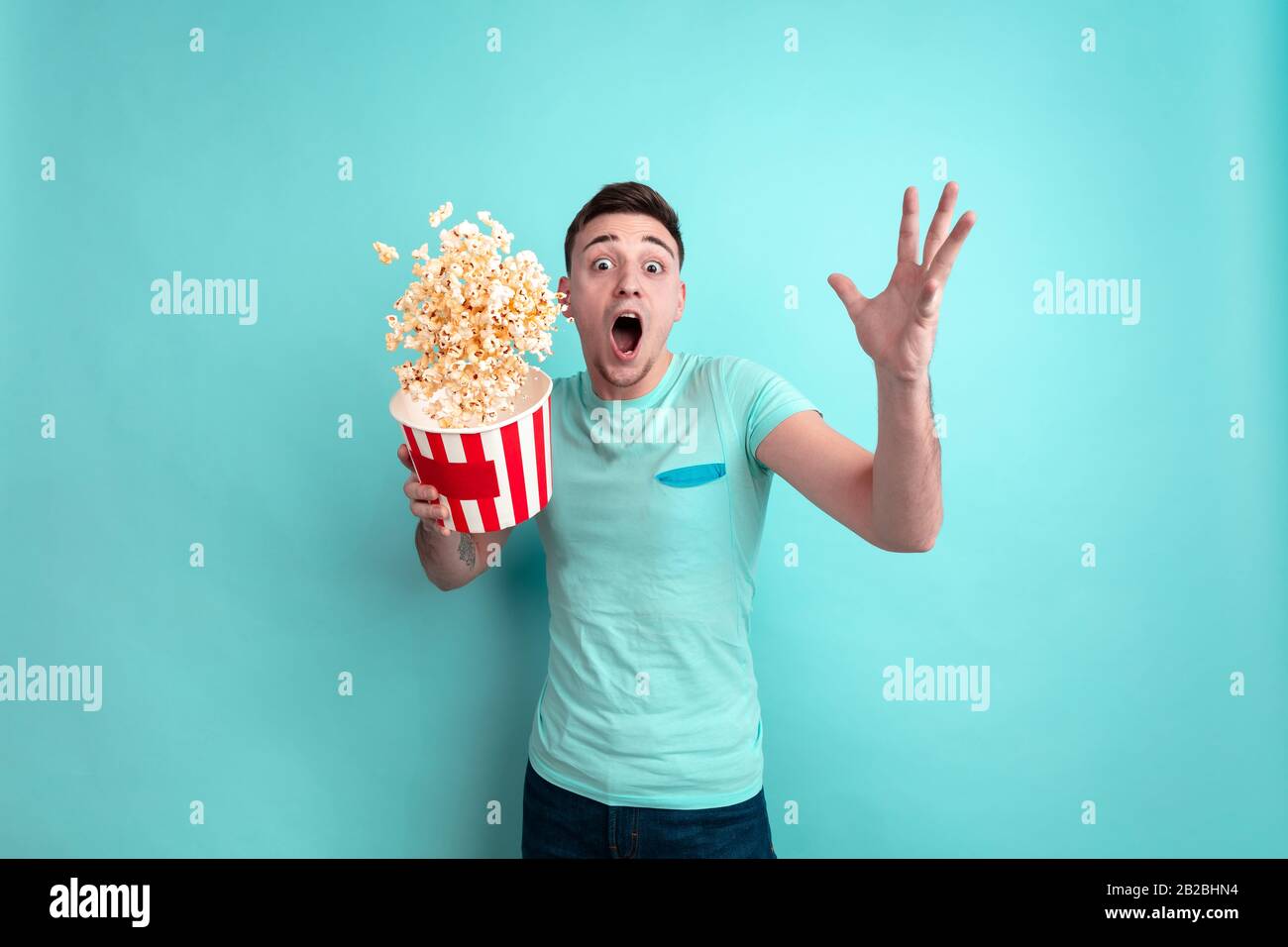 Crazy shocked, flying popcorn. Caucasian young man's portrait isolated ...