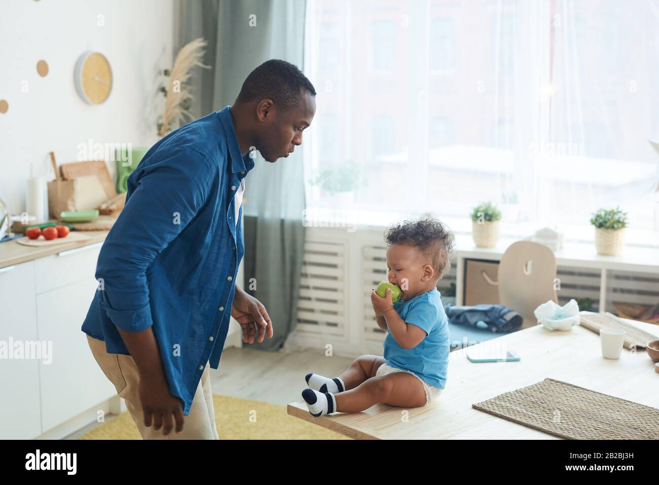 Side view portrait of mature African man trying to calm crying baby in ...
