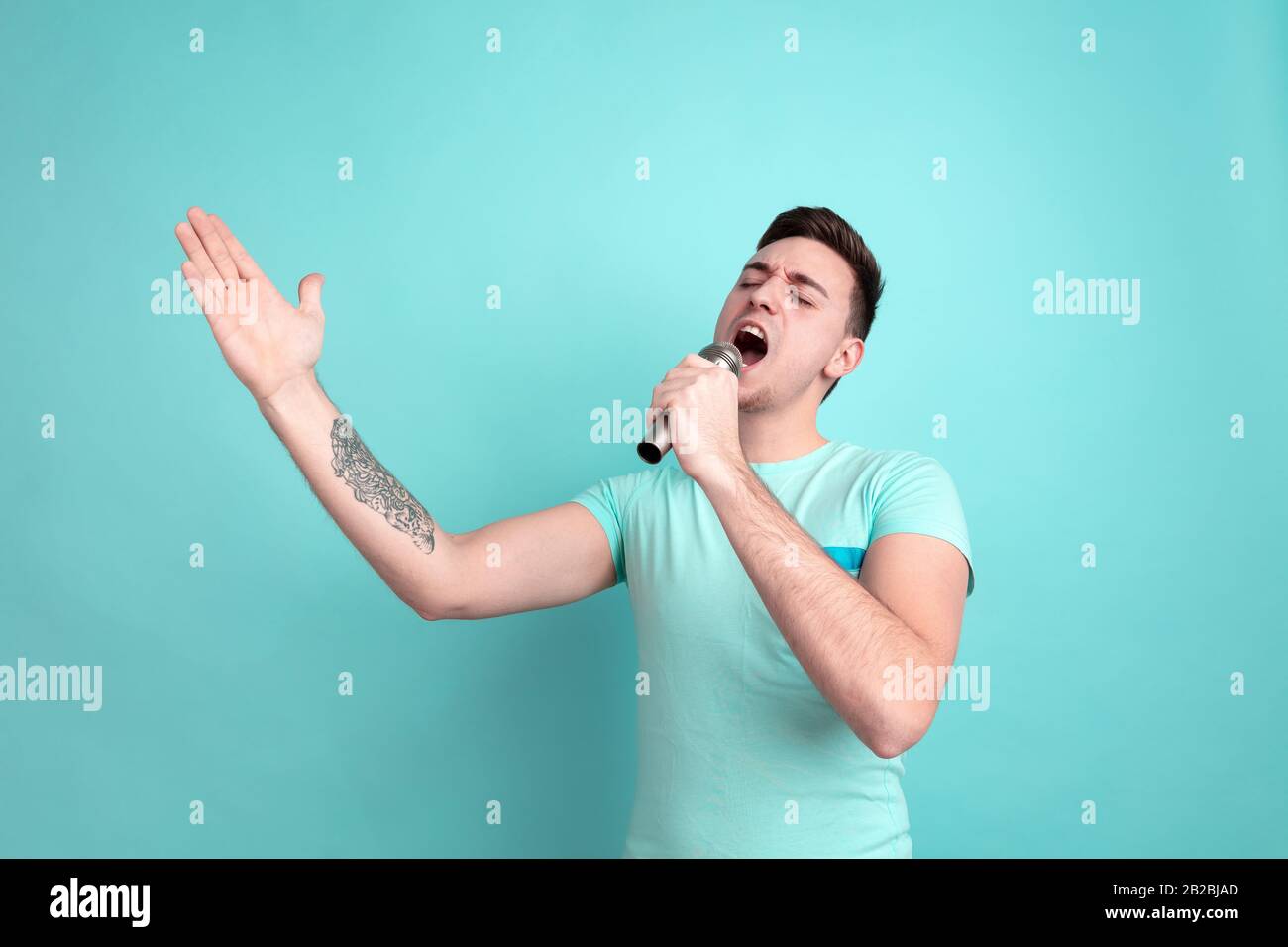 Singing like a star. Caucasian young man's portrait isolated on blue ...