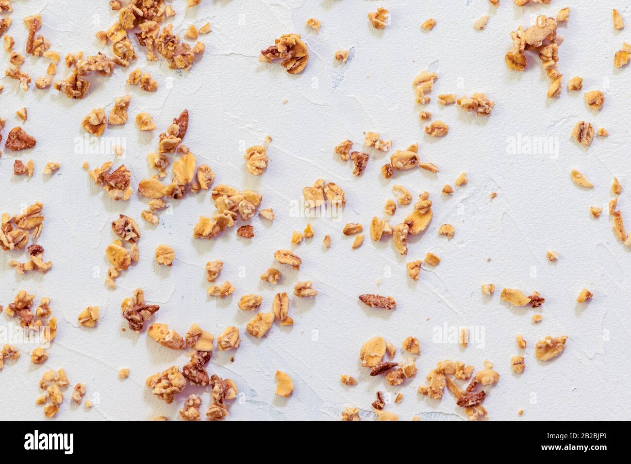 Scattered granola on textured white surface. Food backgrounds Stock ...