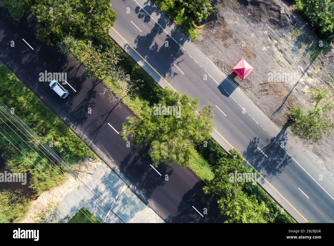 Aerial look down view of road path through the tree with car movement ...