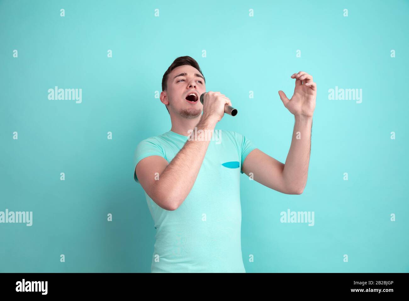 Singing like a star. Caucasian young man's portrait isolated on blue ...
