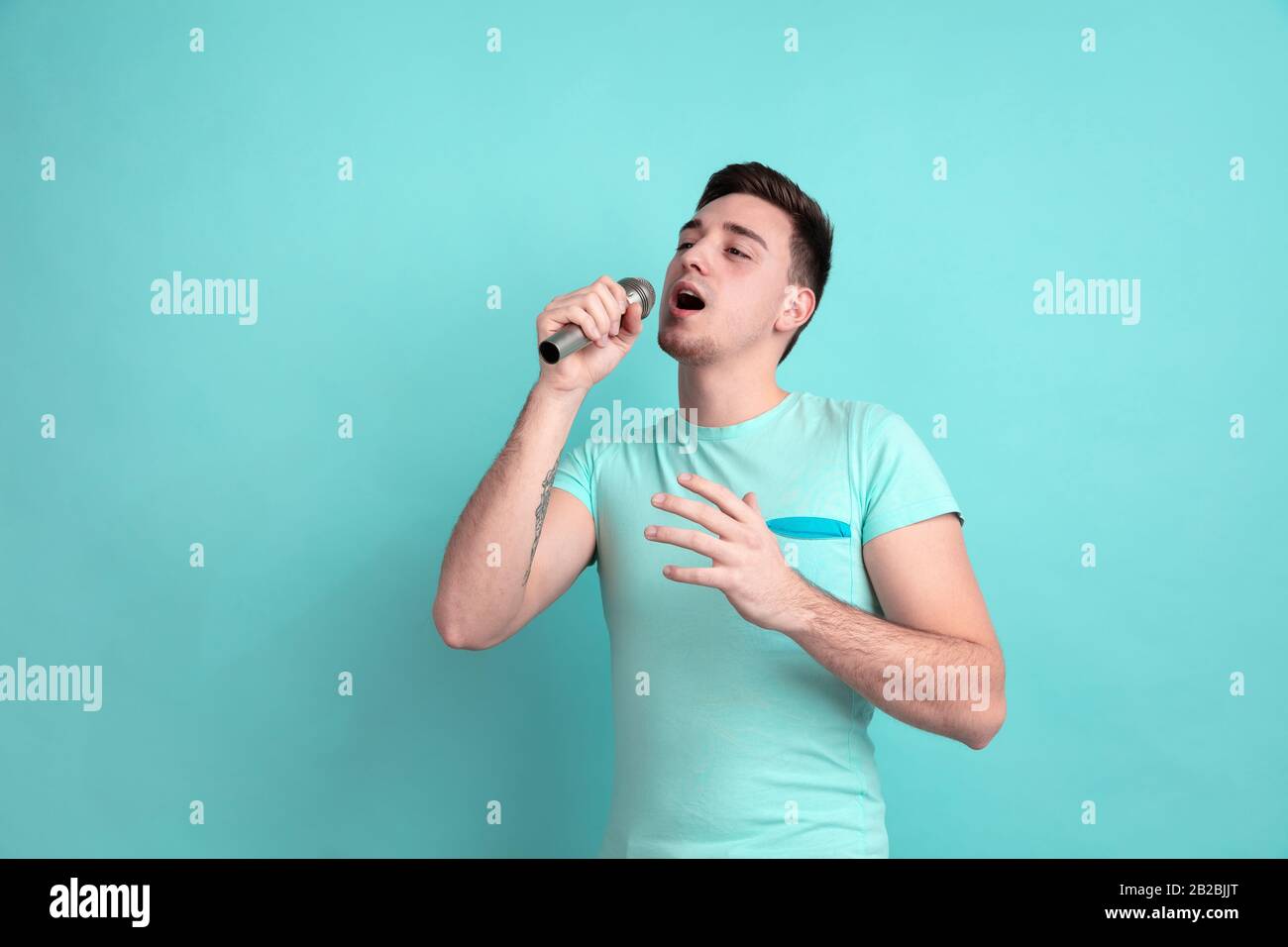 Singing like a star. Caucasian young man's portrait isolated on blue ...