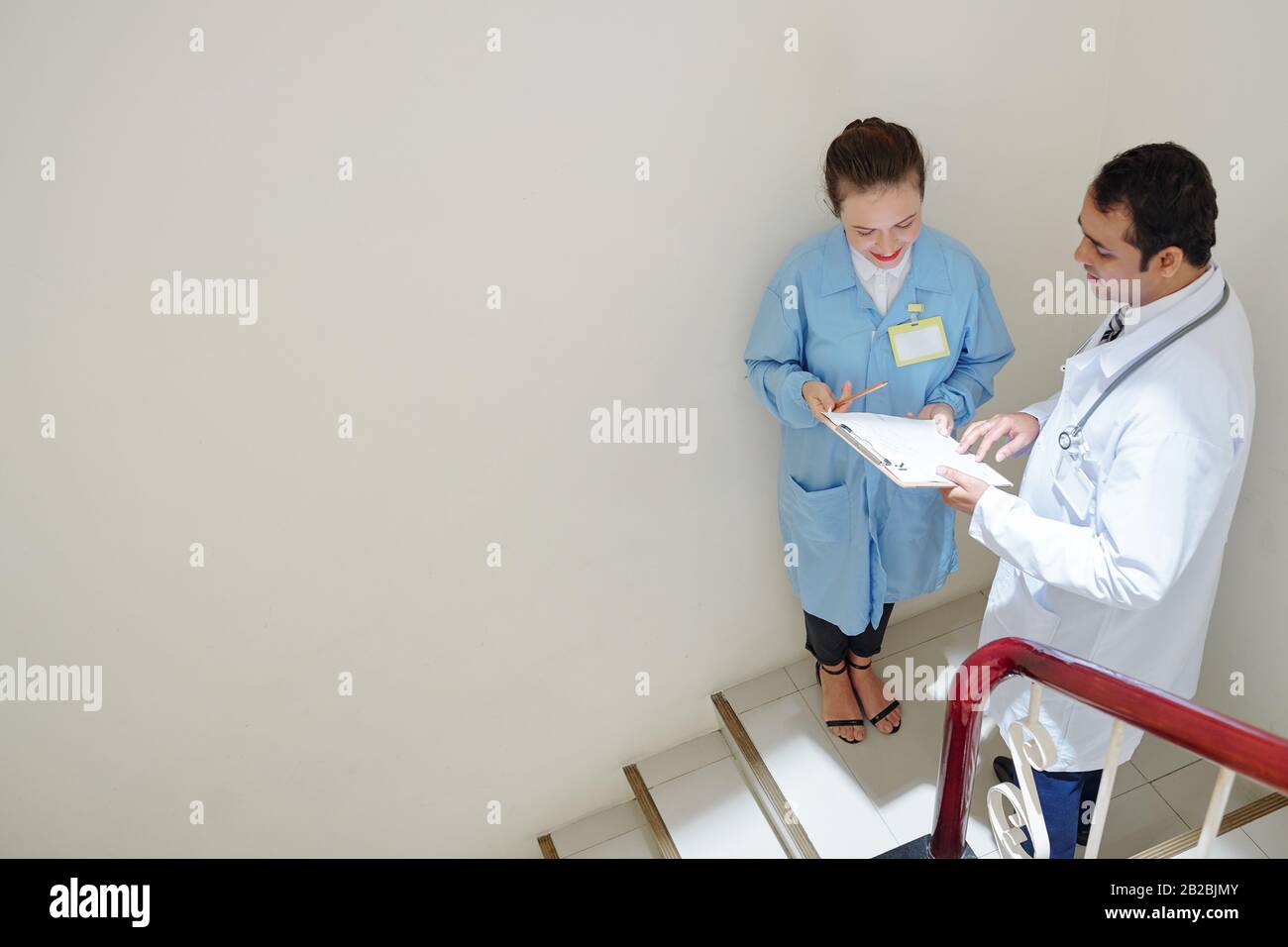 Doctors standing on steps and discussing document with medical ...