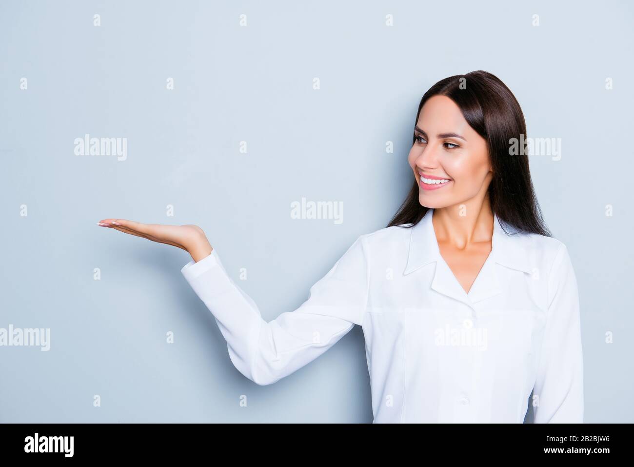 Smiling assistant holding something on hand and demonstrating it Stock ...