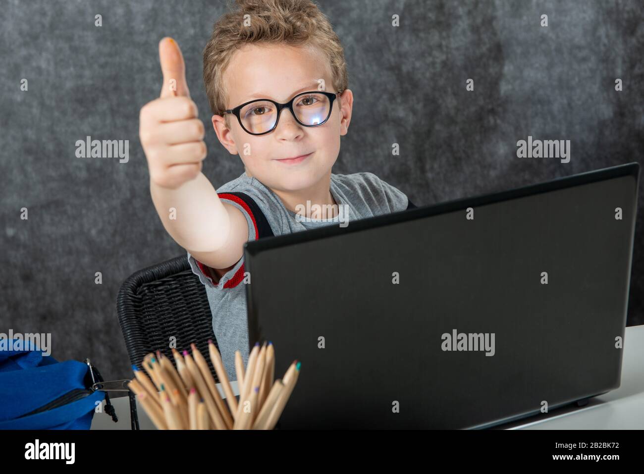 a little school boy with laptop showing OK gesture Stock Photo - Alamy