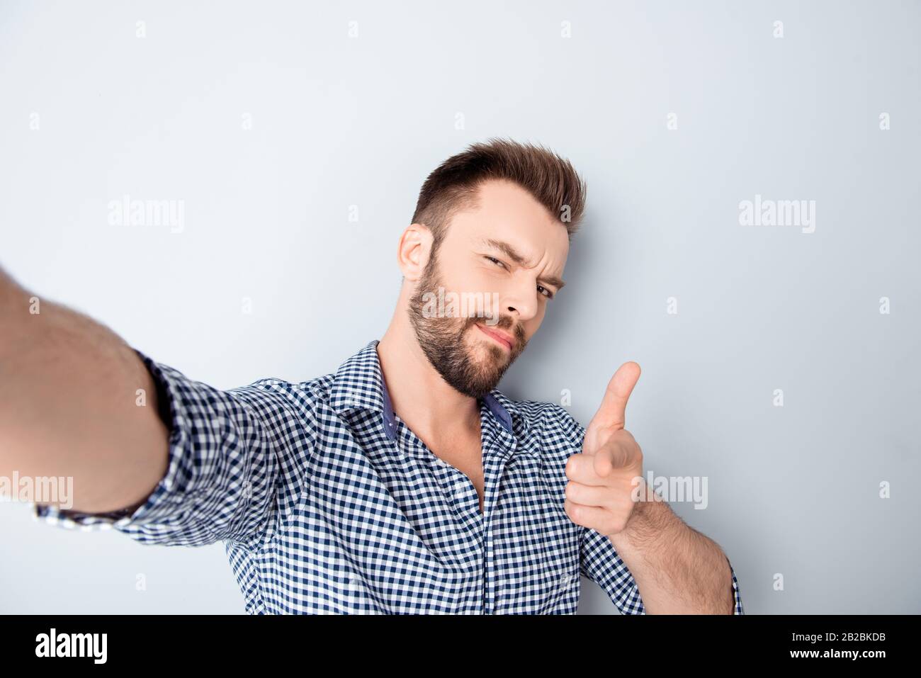 Young handsome man winking and pointing on camera while making selfie ...