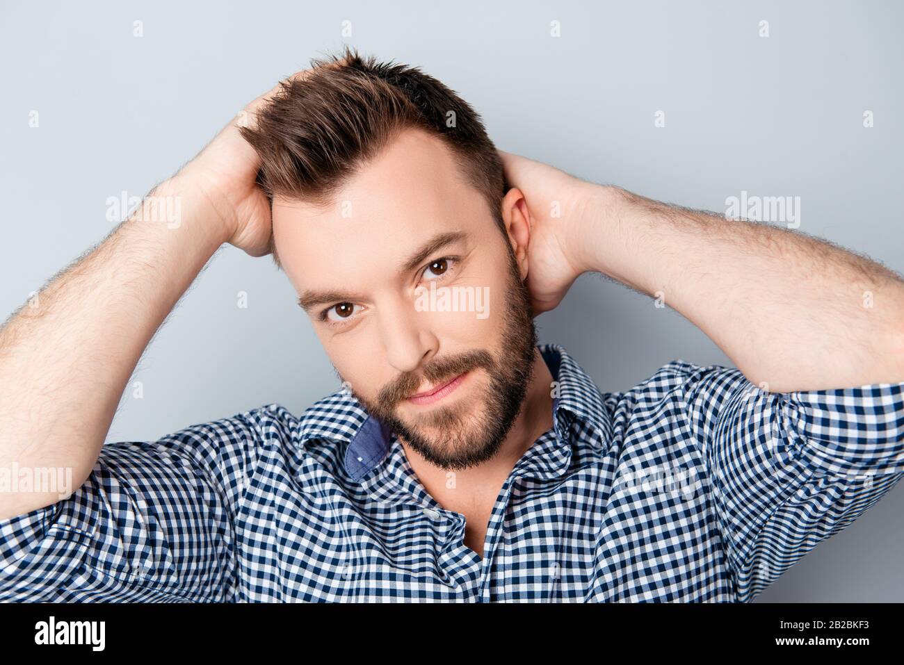 Handsome smiling man holding hands on his hair Stock Photo - Alamy