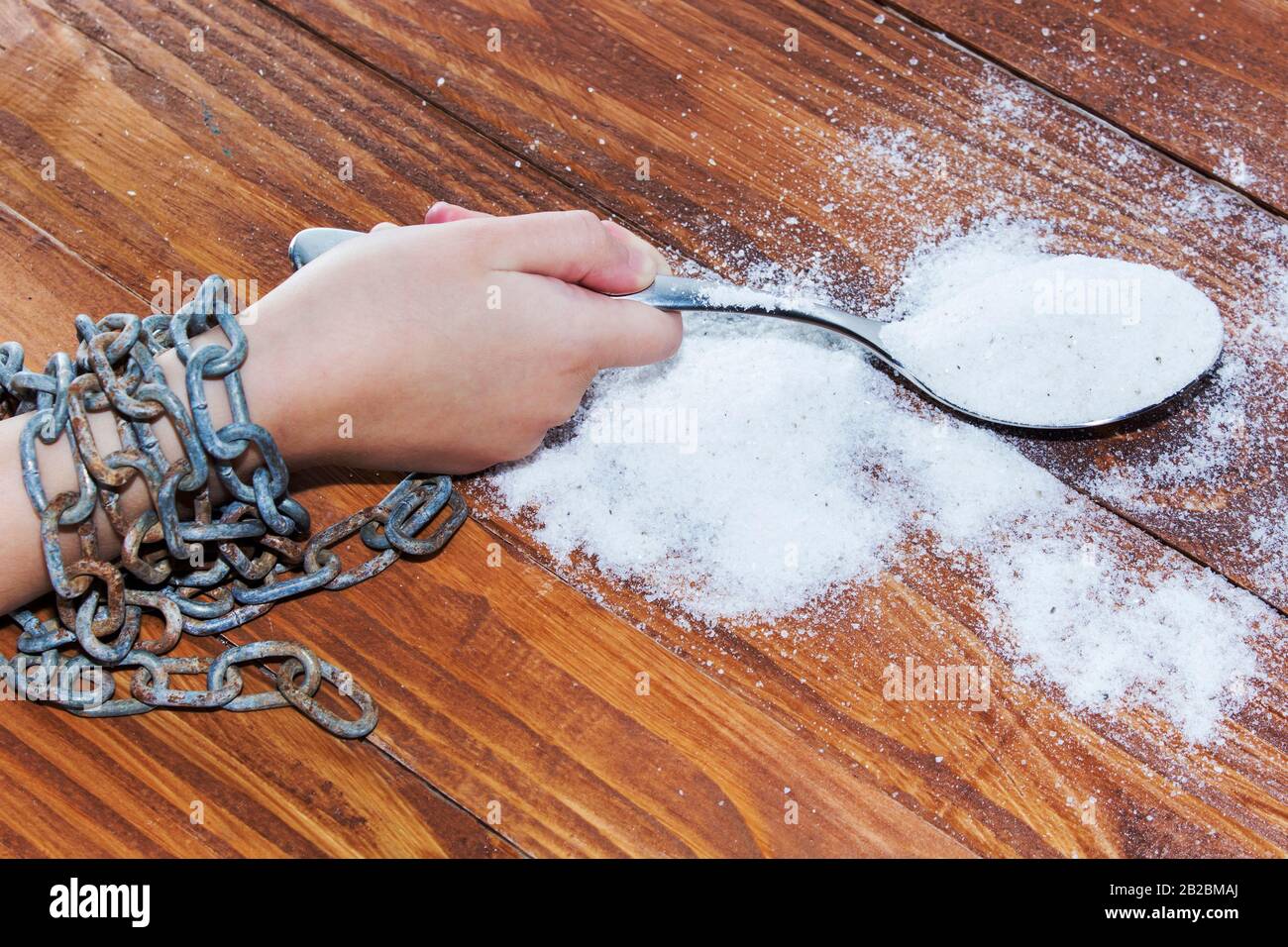 Sea salt in spoon on wooden background. Hands chained in a chain ...