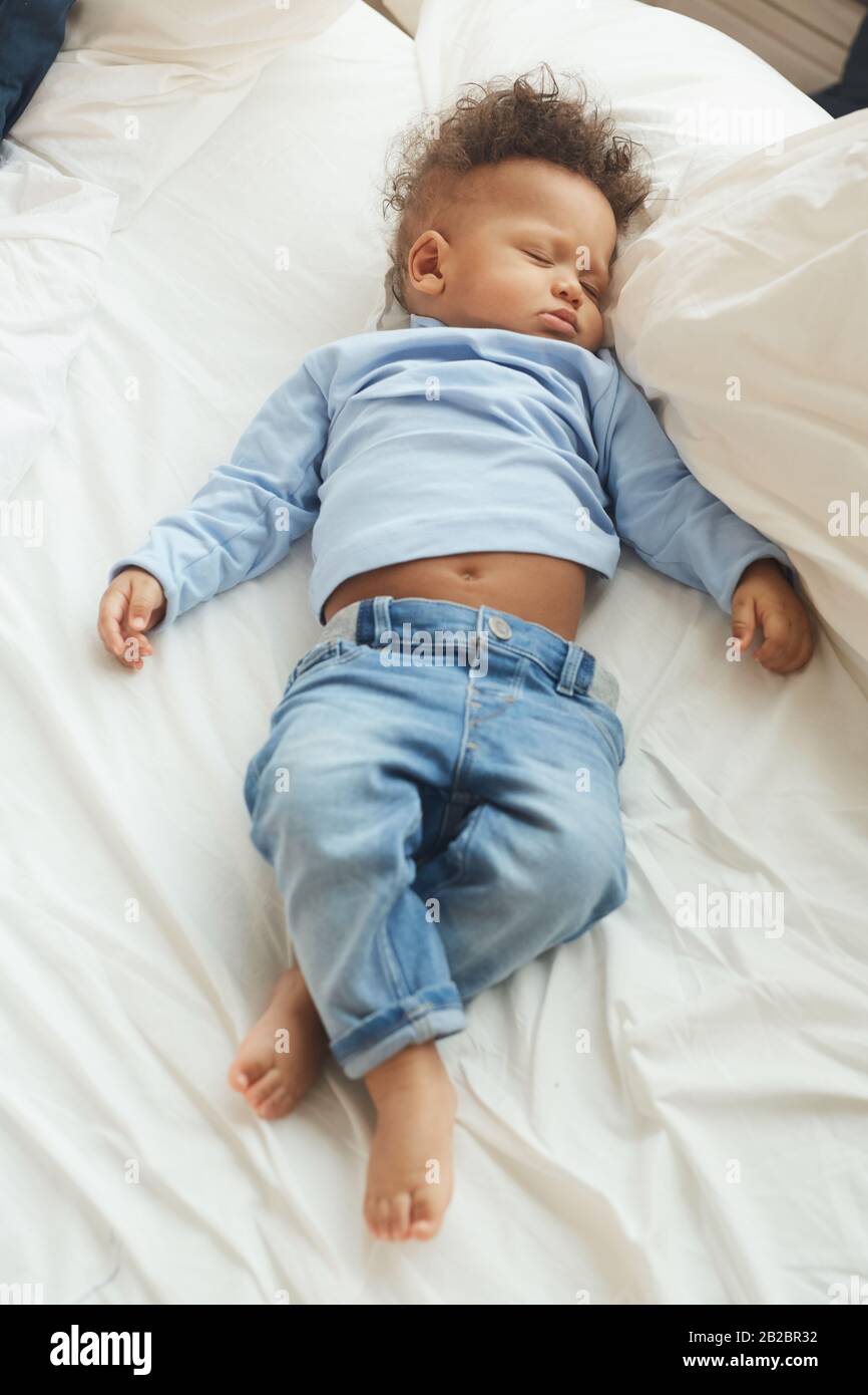 Above view at cute mixed-race baby sleeping on comfortable bed in white ...