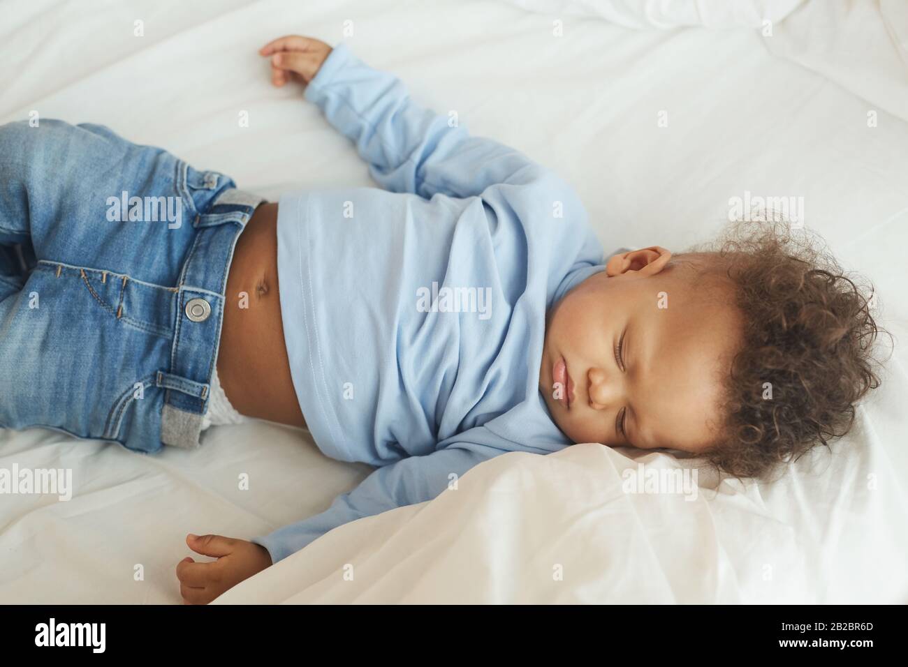 High angle view at cute mixed-race baby sleeping on comfortable bed in ...