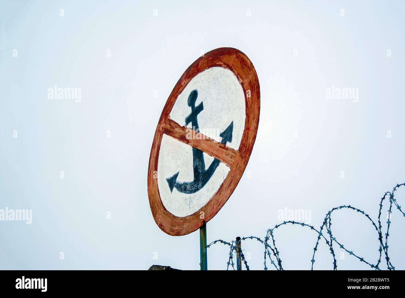 No anchor sign on grey sky backdrop with barbed wires Stock Photo - Alamy