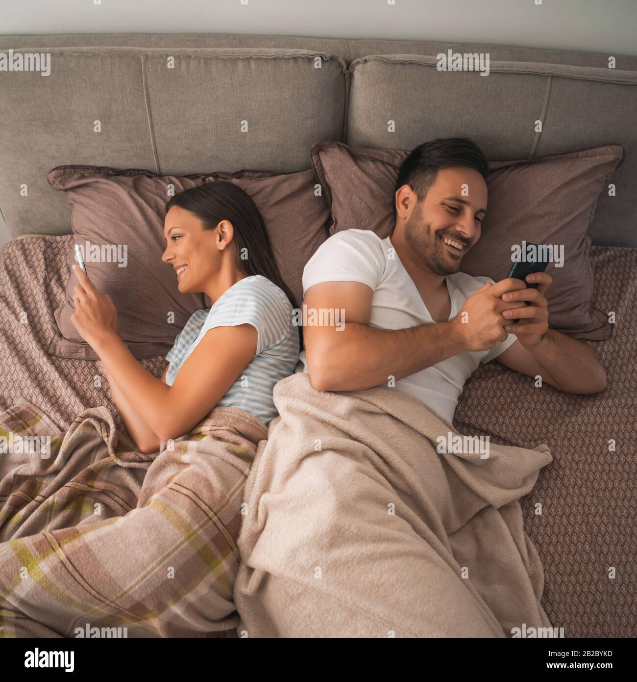 Young couple is resting in bed after work Stock Photo - Alamy