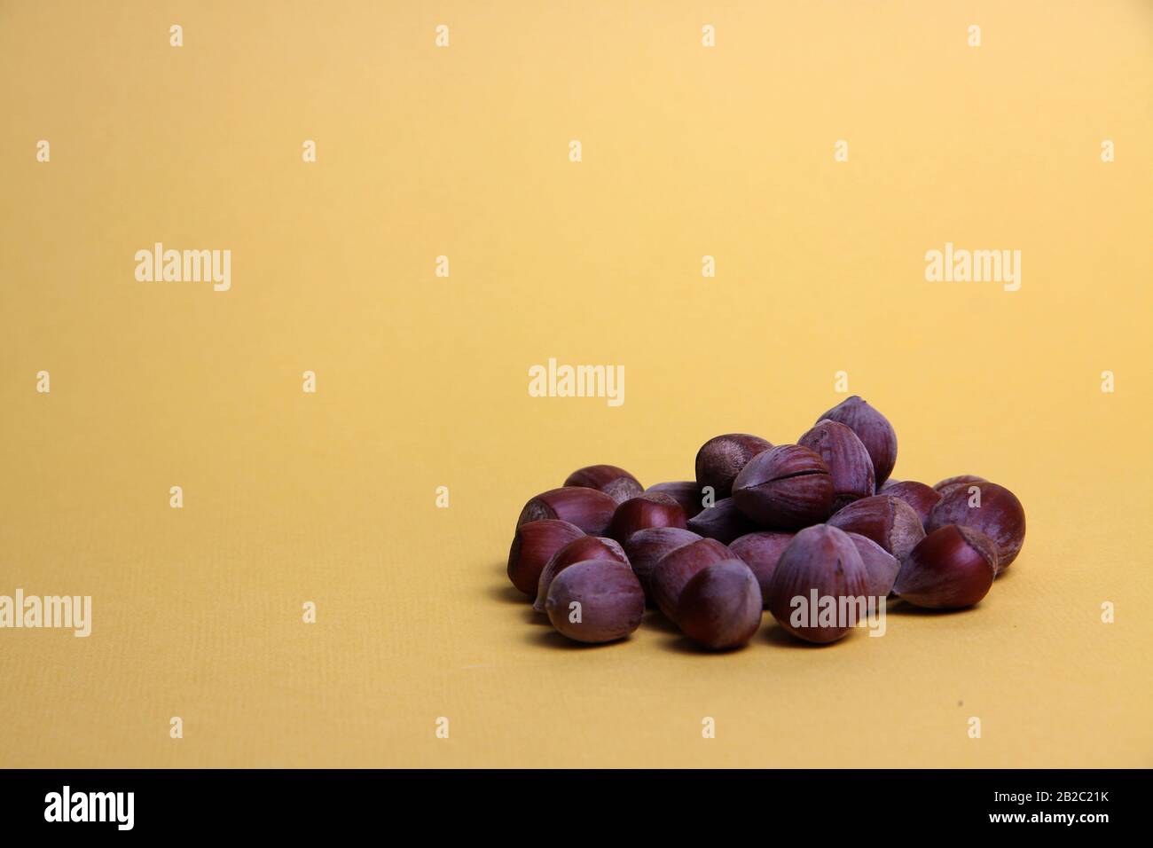 a pile of filbert isolated on yellow background. Image contains copy ...