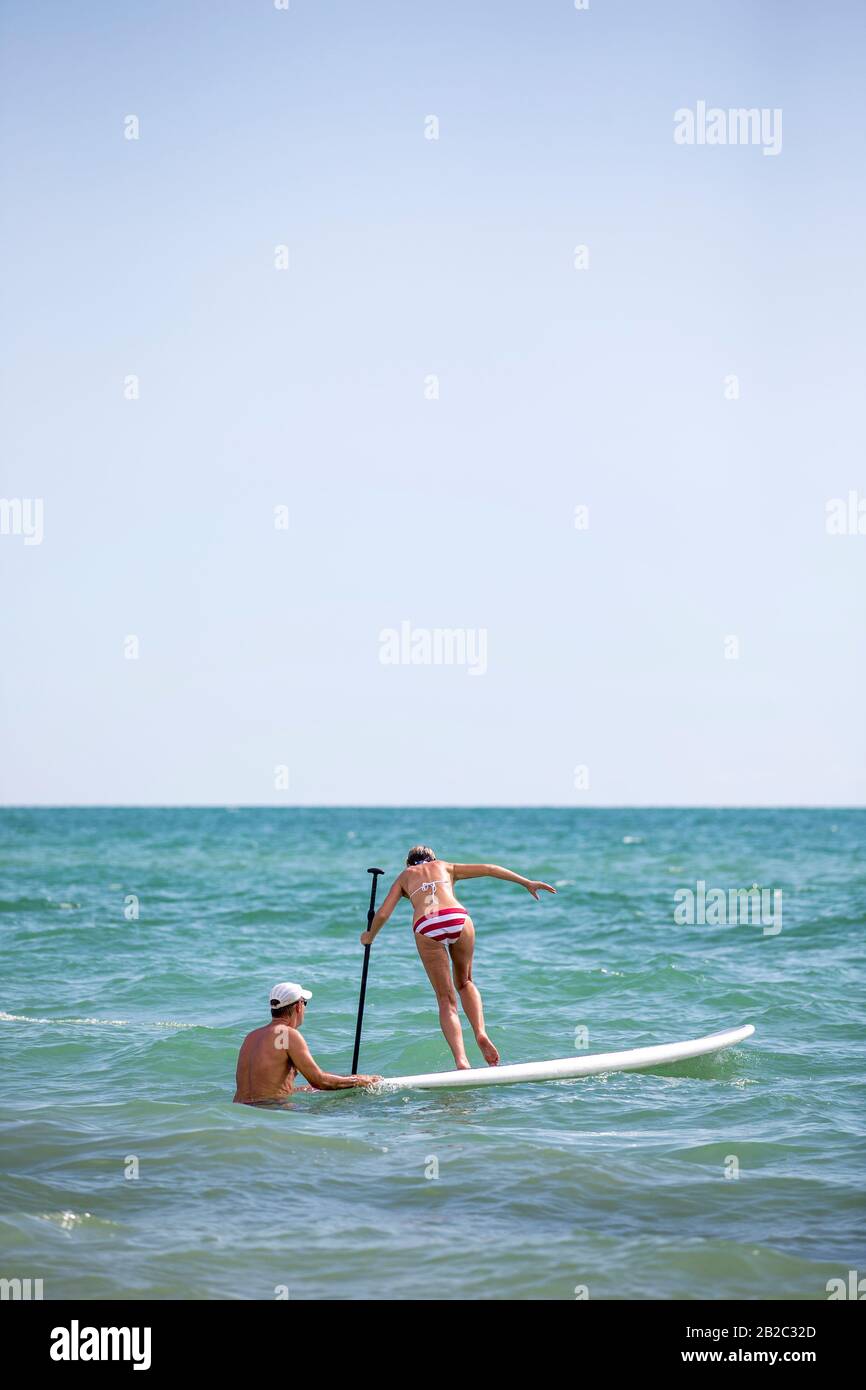 A women, paddle boarding is loosing balance and jumping or rather ...