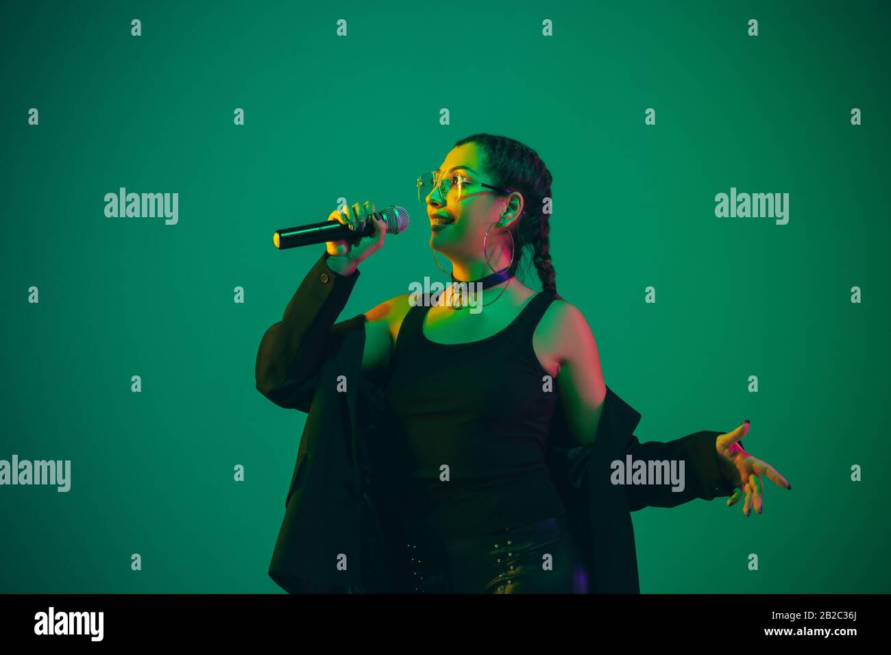 Caucasian female singer portrait isolated on green studio background in ...