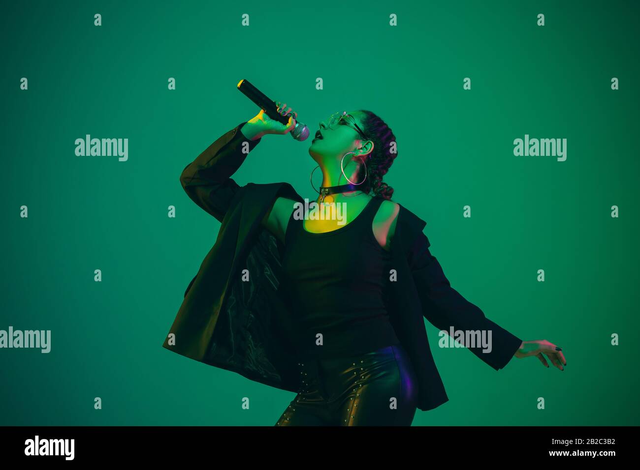 Caucasian female singer portrait isolated on green studio background in ...
