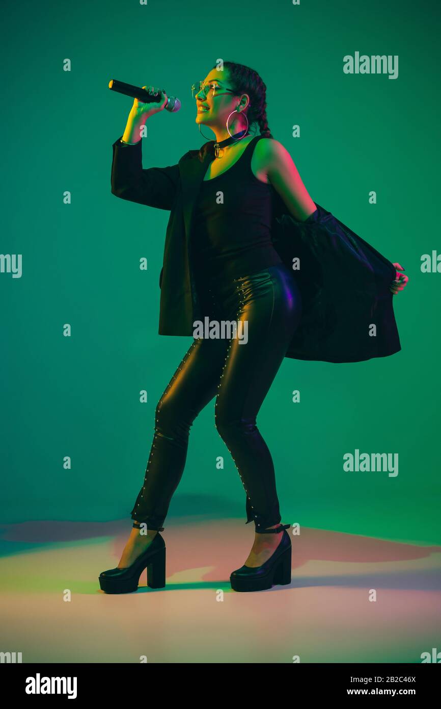 Caucasian female singer portrait isolated on green studio background in ...